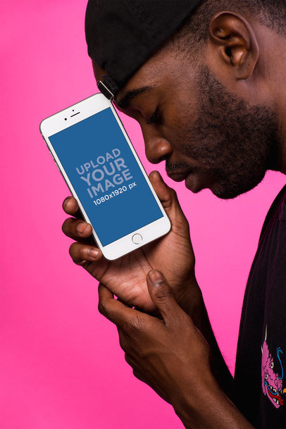 Placeit - Mockup of a Man with a Holding an iPhone Against a Yellow Wall