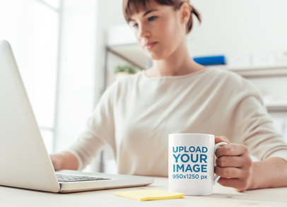 Placeit - Mockup of a Woman Drinking From an 11 oz Coffee Mug While Working