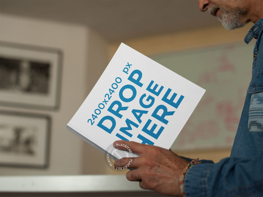 Placeit - Mockup of a Man Reading a Square Book While in his House